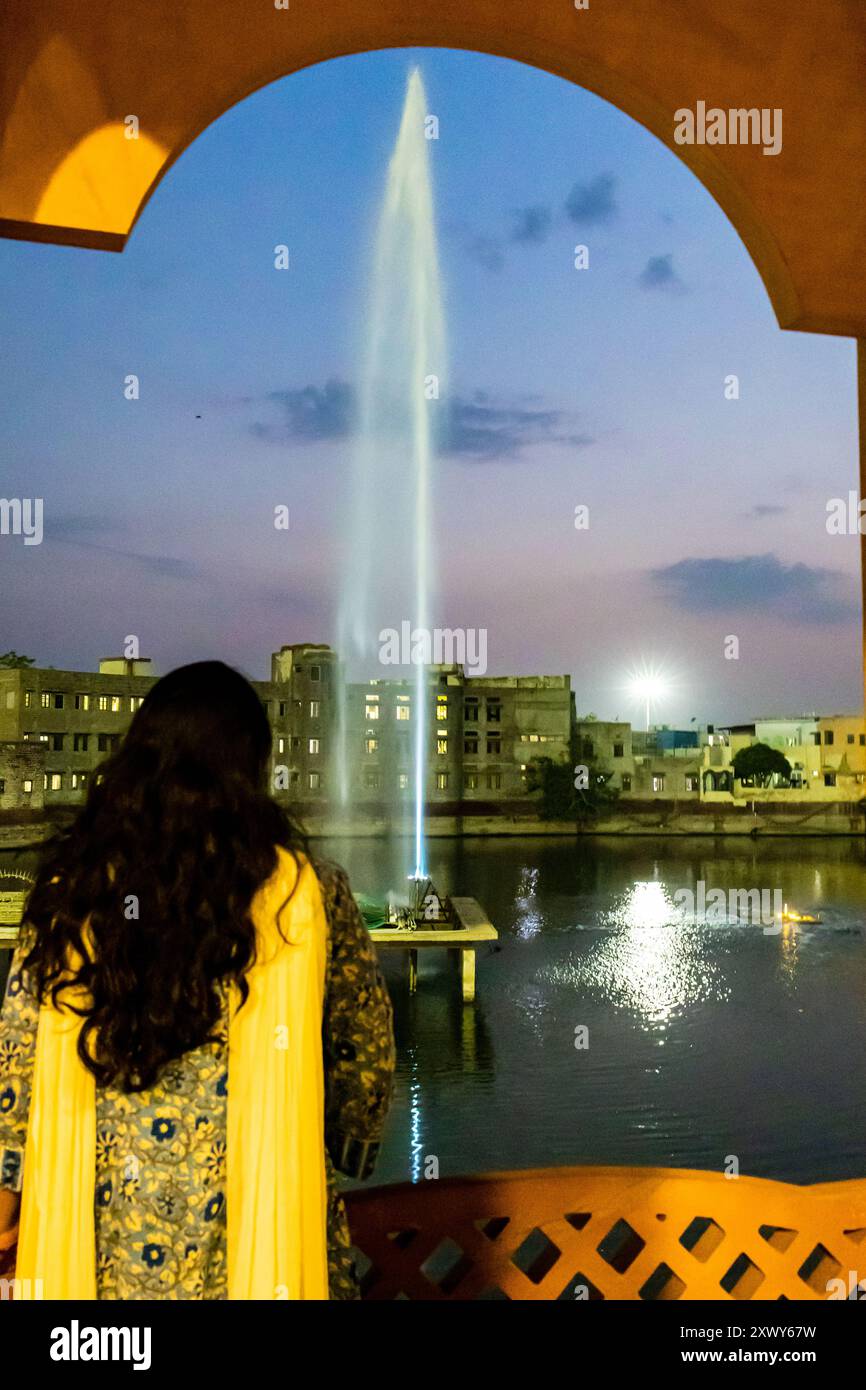 girl watching water fountain with long water throw with dramatic sky at ...