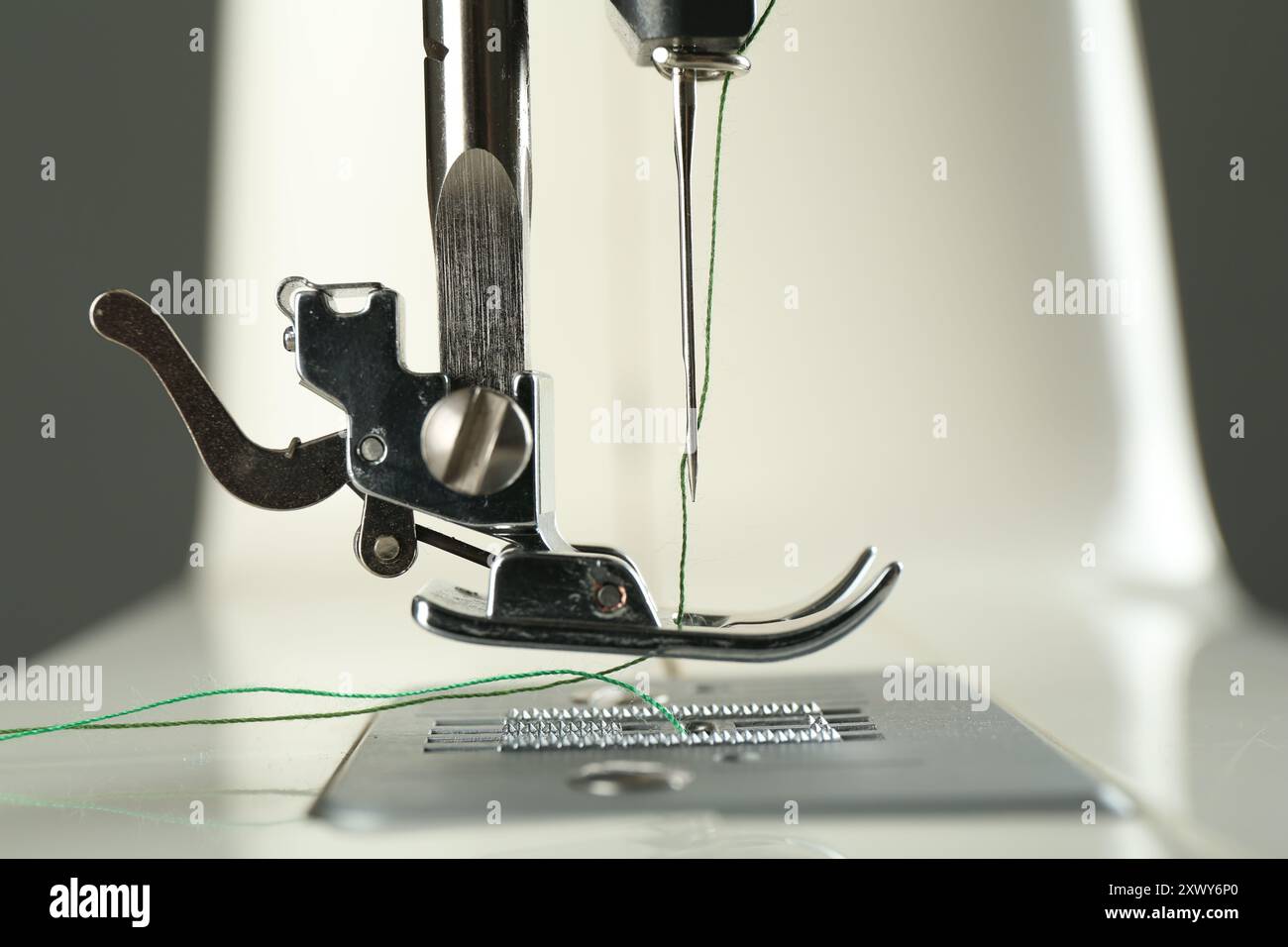 Sewing machine with green thread on grey background, closeup Stock ...