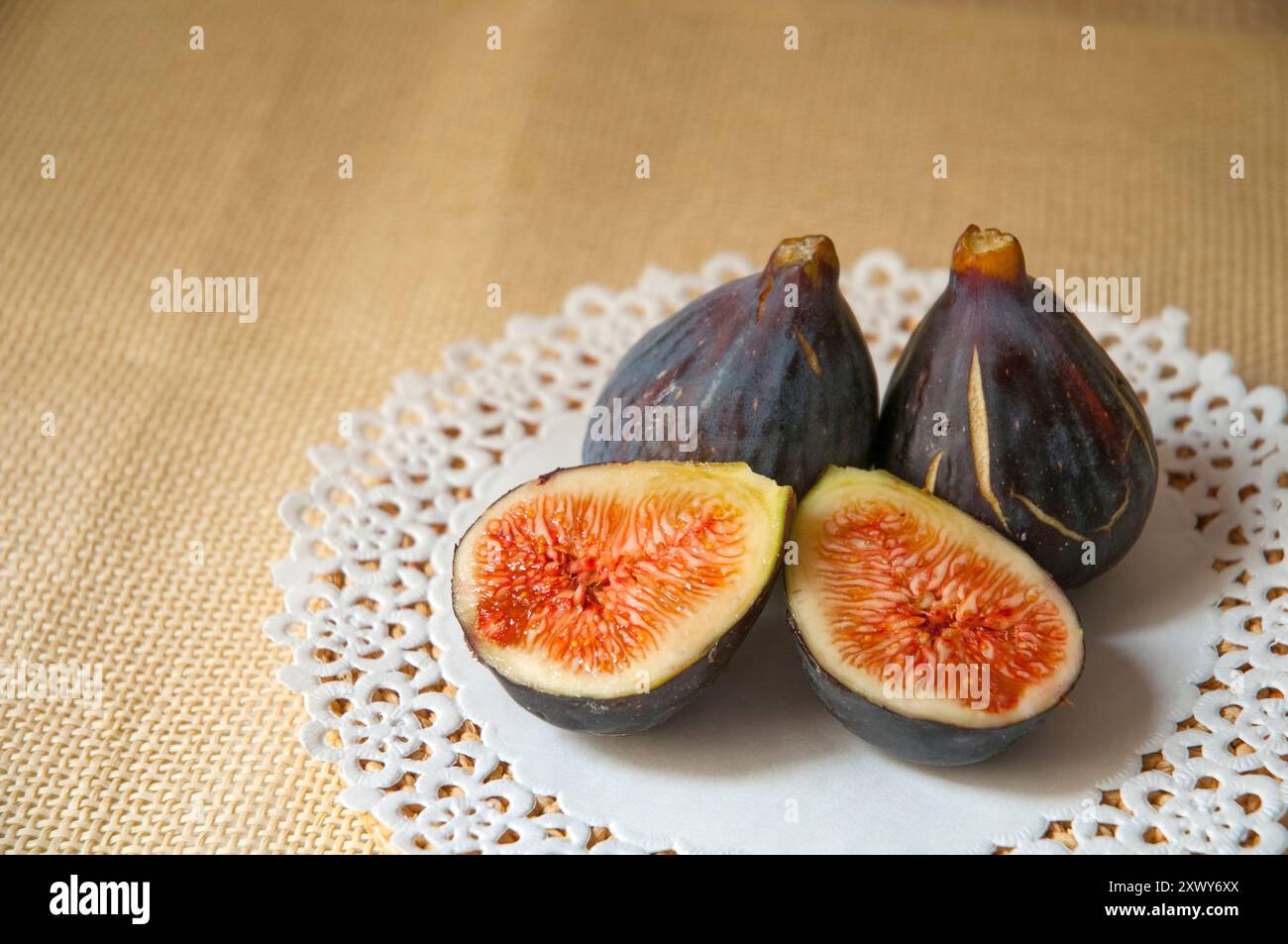 Three black figs, one of them cut in two halves Stock Photo - Alamy