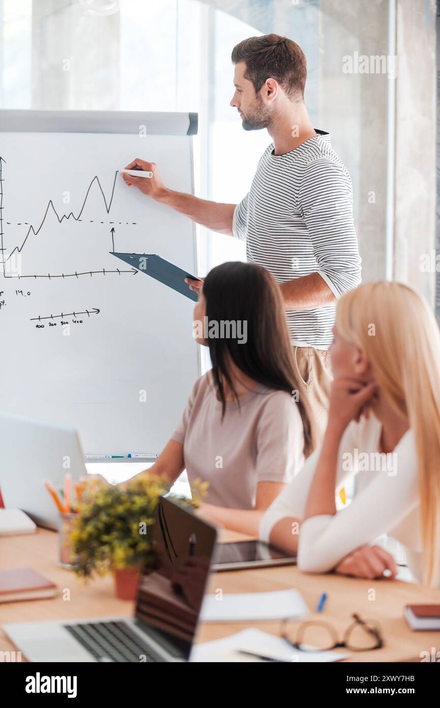 Business presentation. Confident young man standing near whiteboard and ...