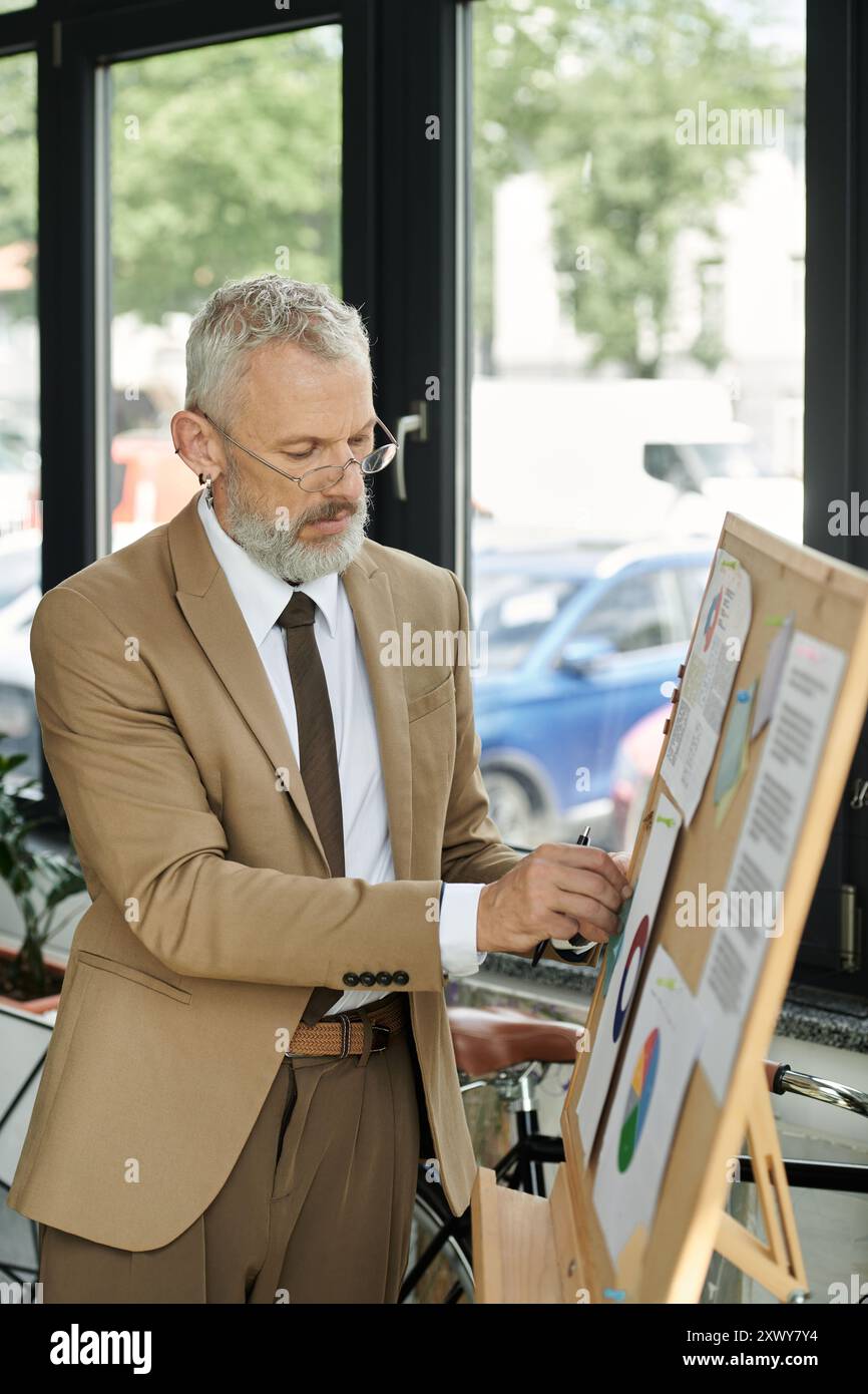 A man in a suit stands by a whiteboard, explaining charts with a pen in ...
