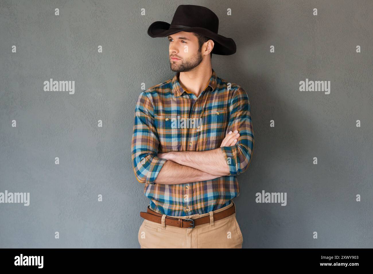 Serious and confident cowboy. Handsome young man in cowboy hat keeping ...