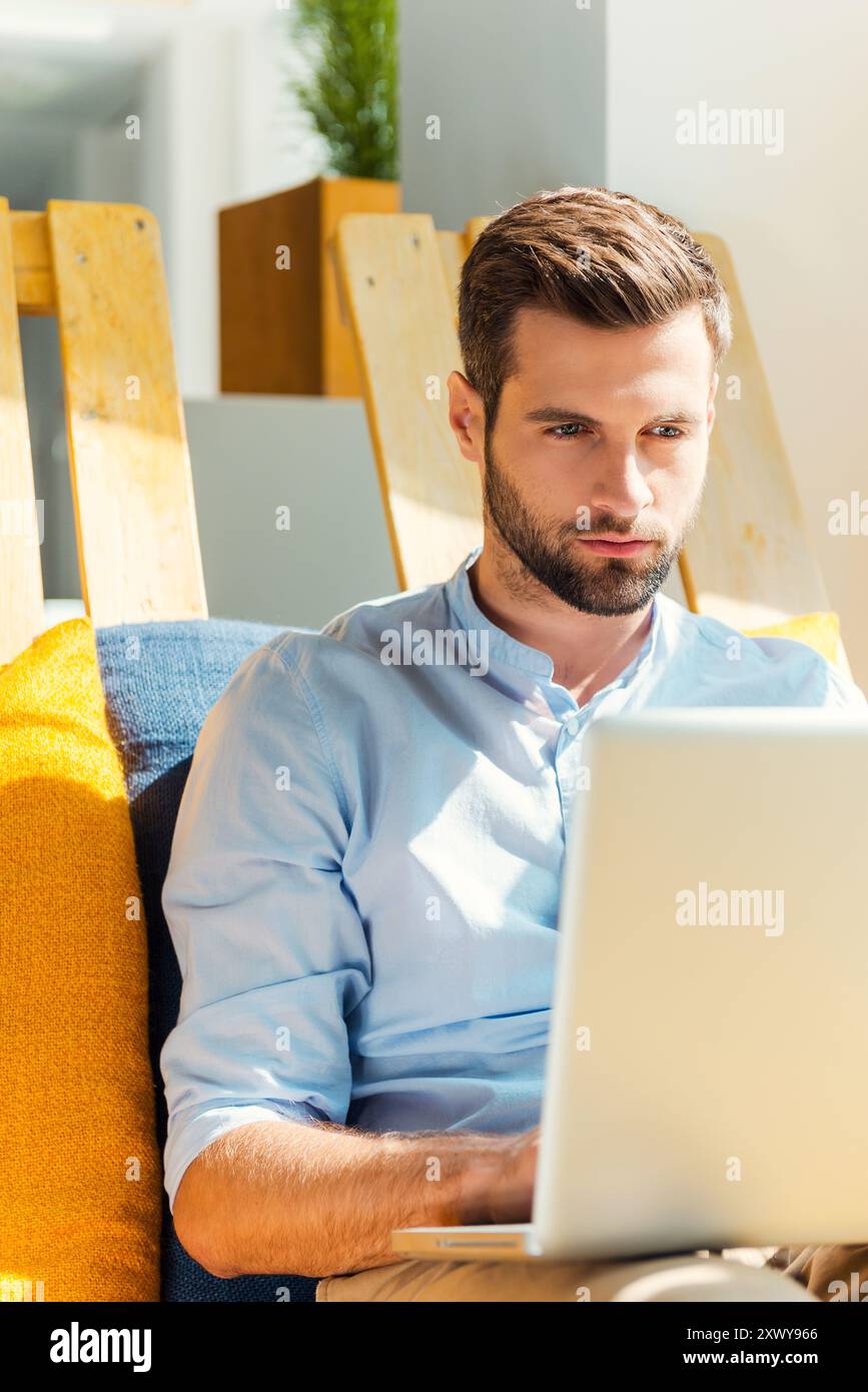 Hard work brings rewards. Concentrated young man working on laptop ...
