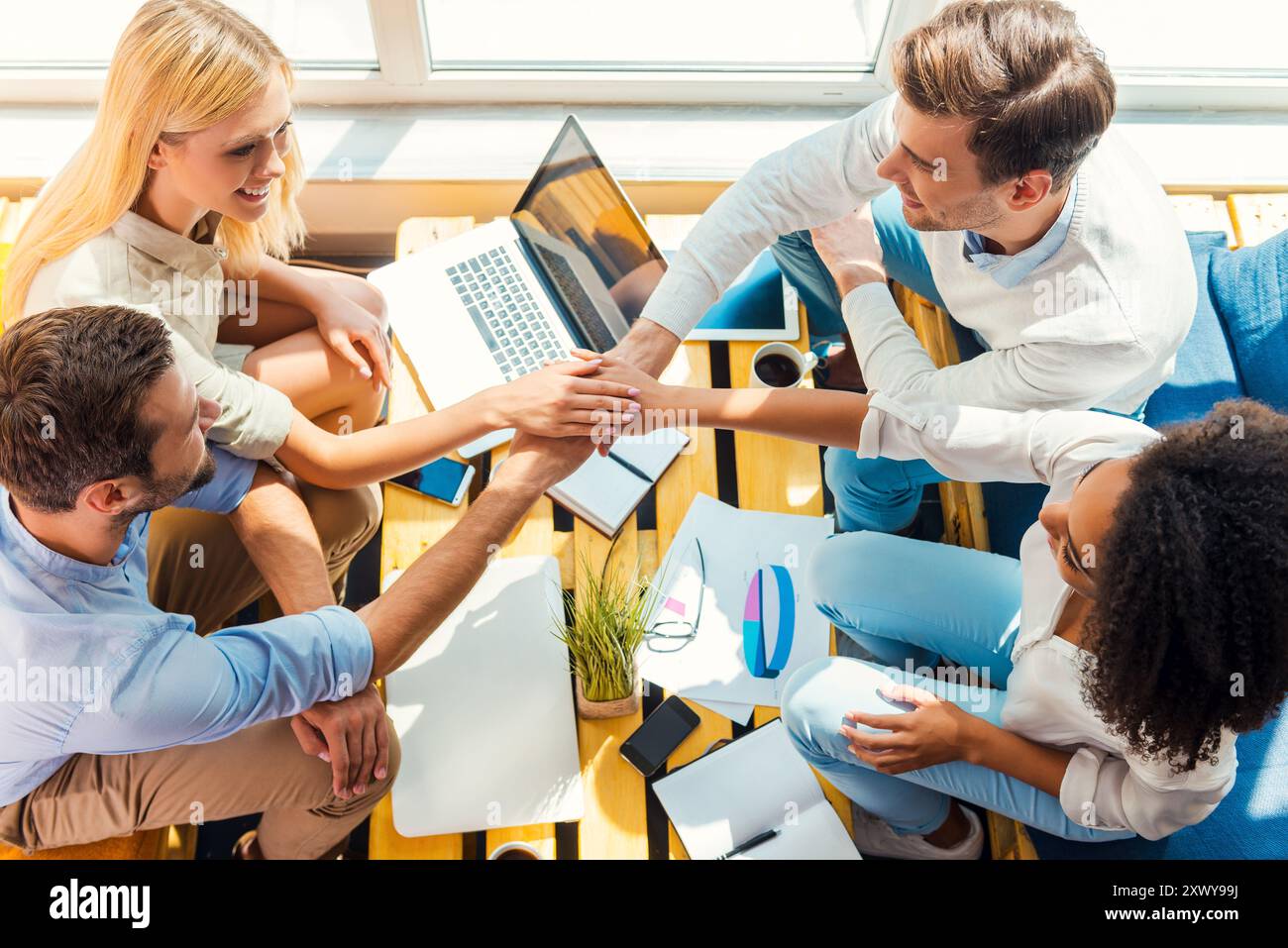 Good job team! Top view of four happy young people holding hands ...