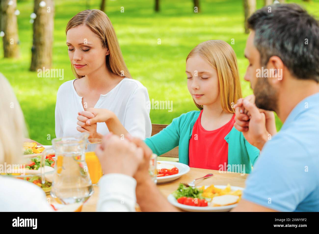 Thanking God for the meal. Family holding hands and praying before ...