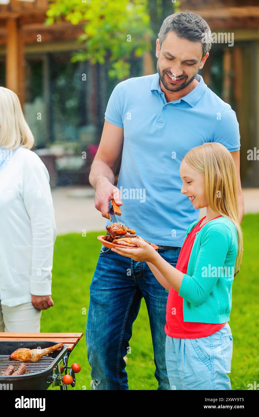 Want some more? Happy family of five people barbecuing meat on grill on ...