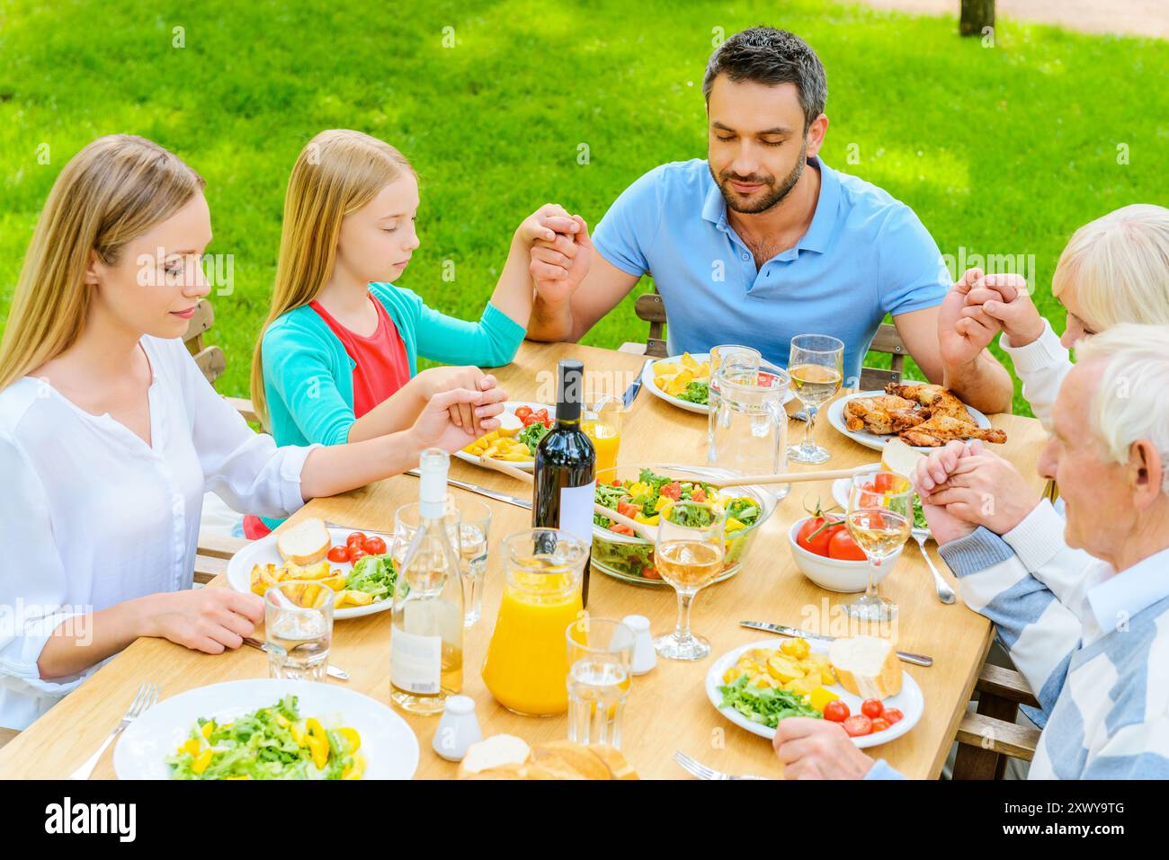 Praying before dinner. Top view of family of five people holding hands ...