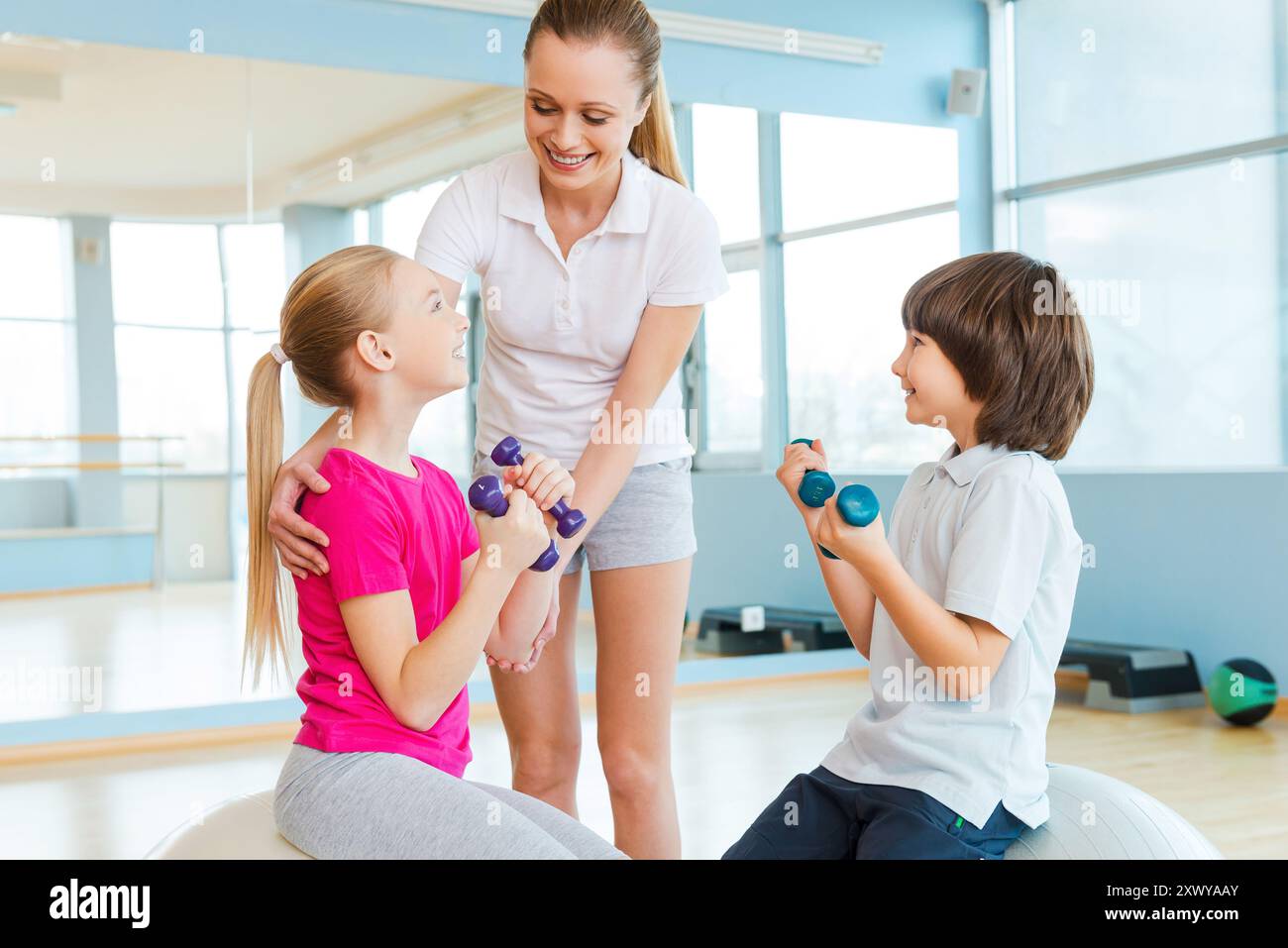 Supporting kids in training. Cheerful instructor helping children with ...