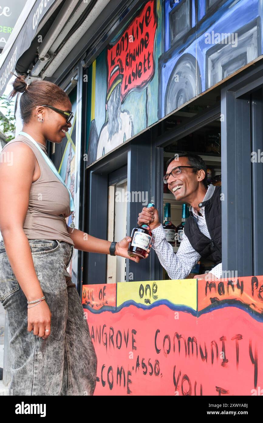 EDITORIAL USE ONLY Shop keeper Nayan serves Abisola Oke in front of a ...