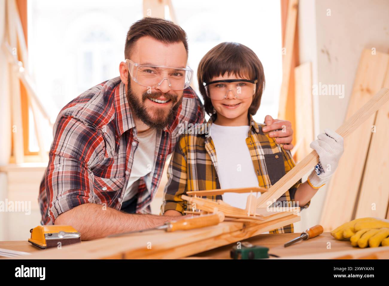 Carpentry is a family business. Cheerful young male carpenter embracing ...