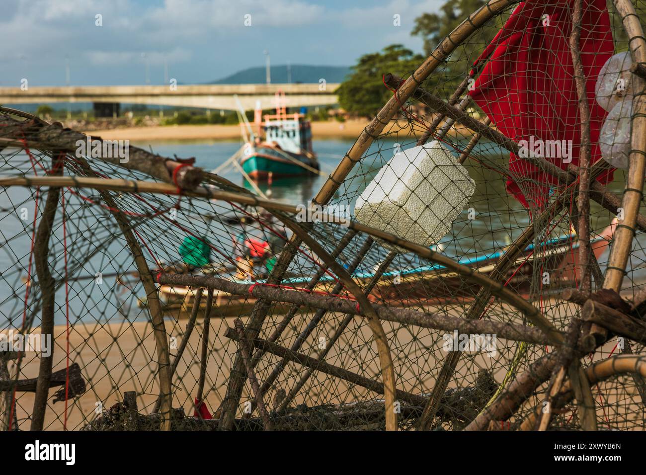 Fish traps piled up on the shore with a fishing boat in the background ...