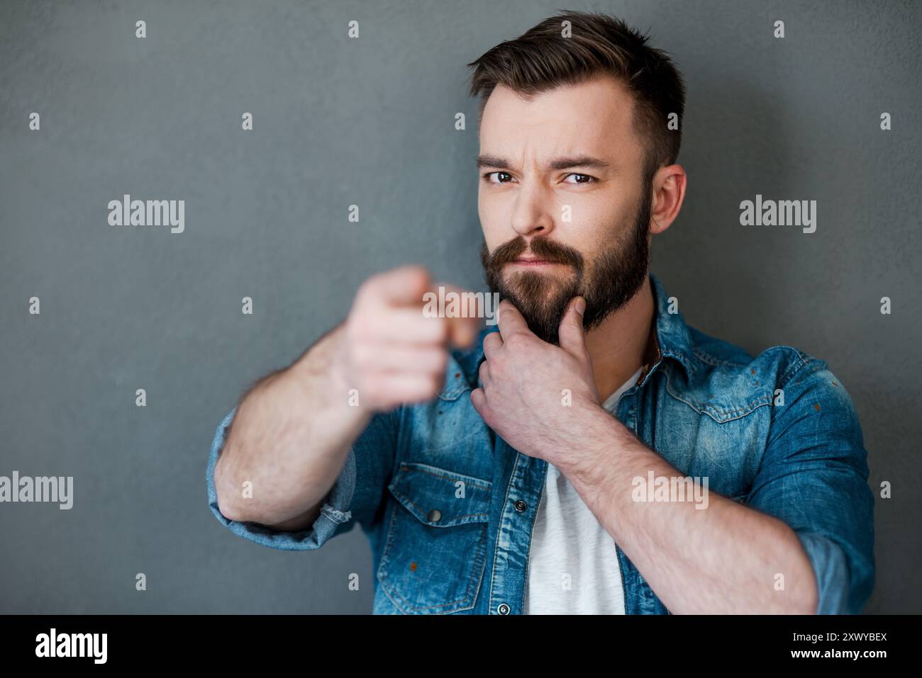 I think you must do it!Serious young man holding hand on chin and ...