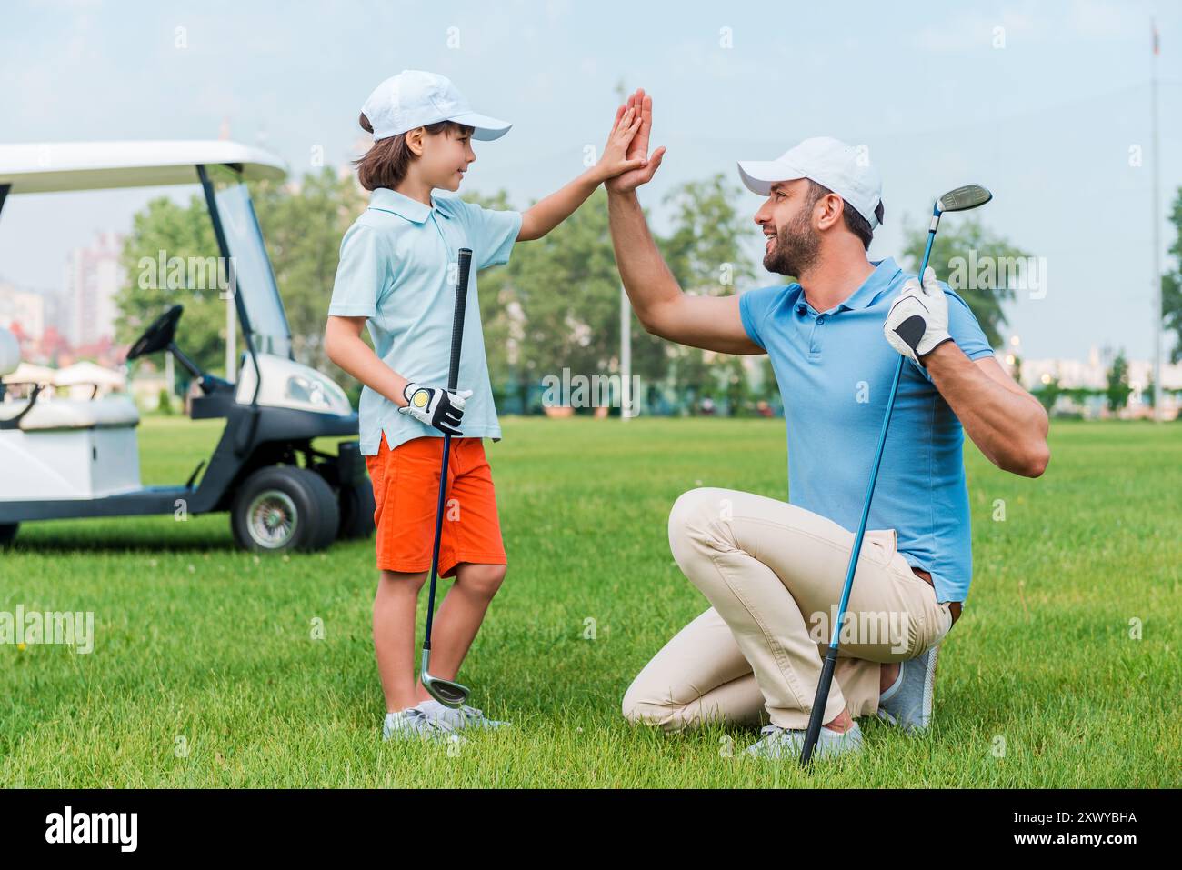 My little winner! Cheerful young man and his son giving high-five to ...