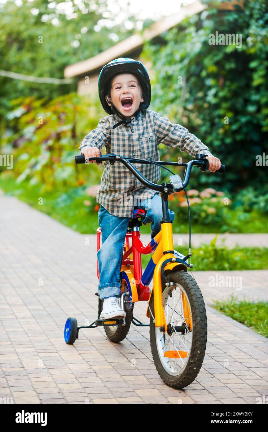 Cycling with fun. Joyful little boy keeping mouth opened and expressing ...