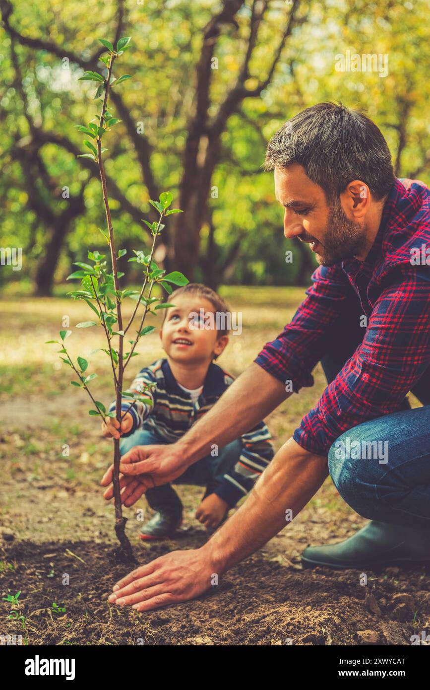 We are doing everything together. Happy young man planting a tree while ...