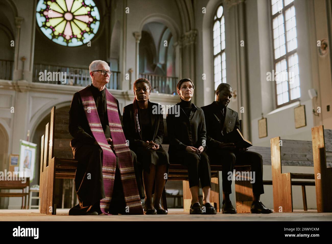 Senior pastor and sorrowful relatives dressed in total black sitting on ...