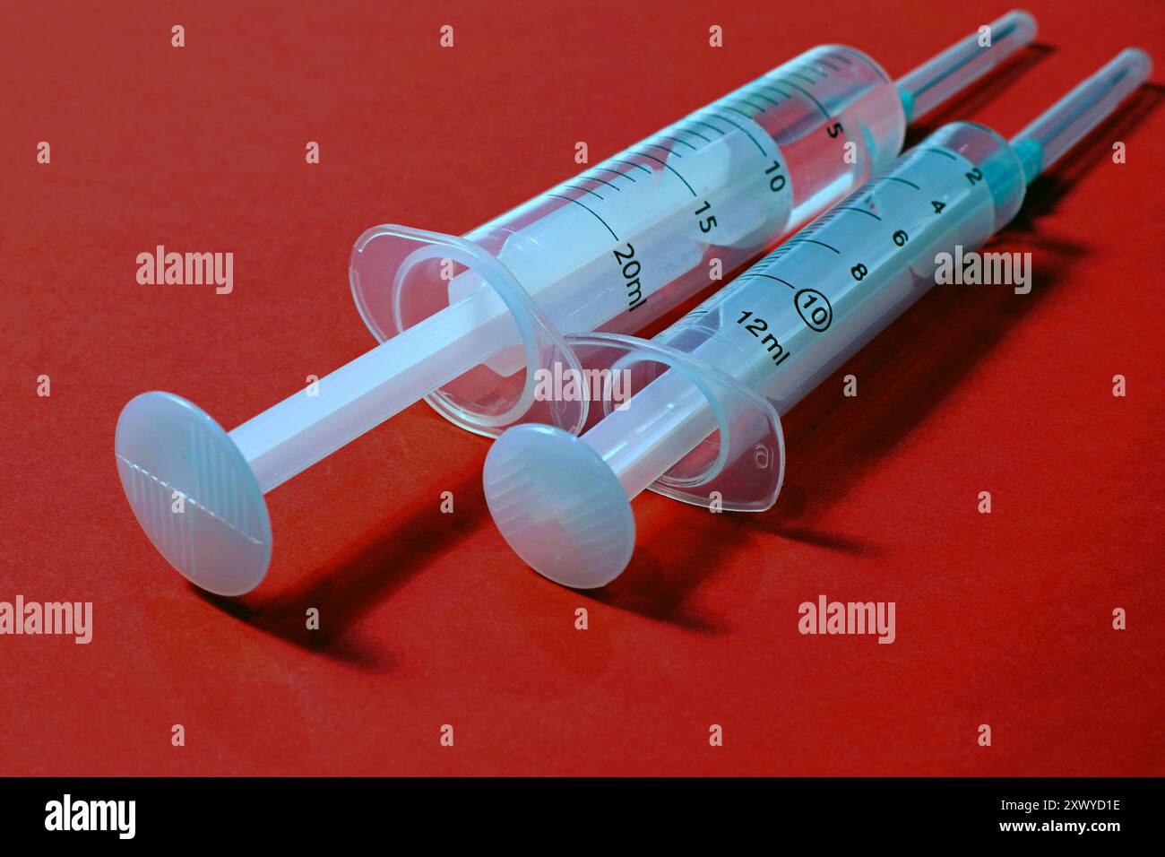 Image of two medical syringes on a red background Stock Photo - Alamy