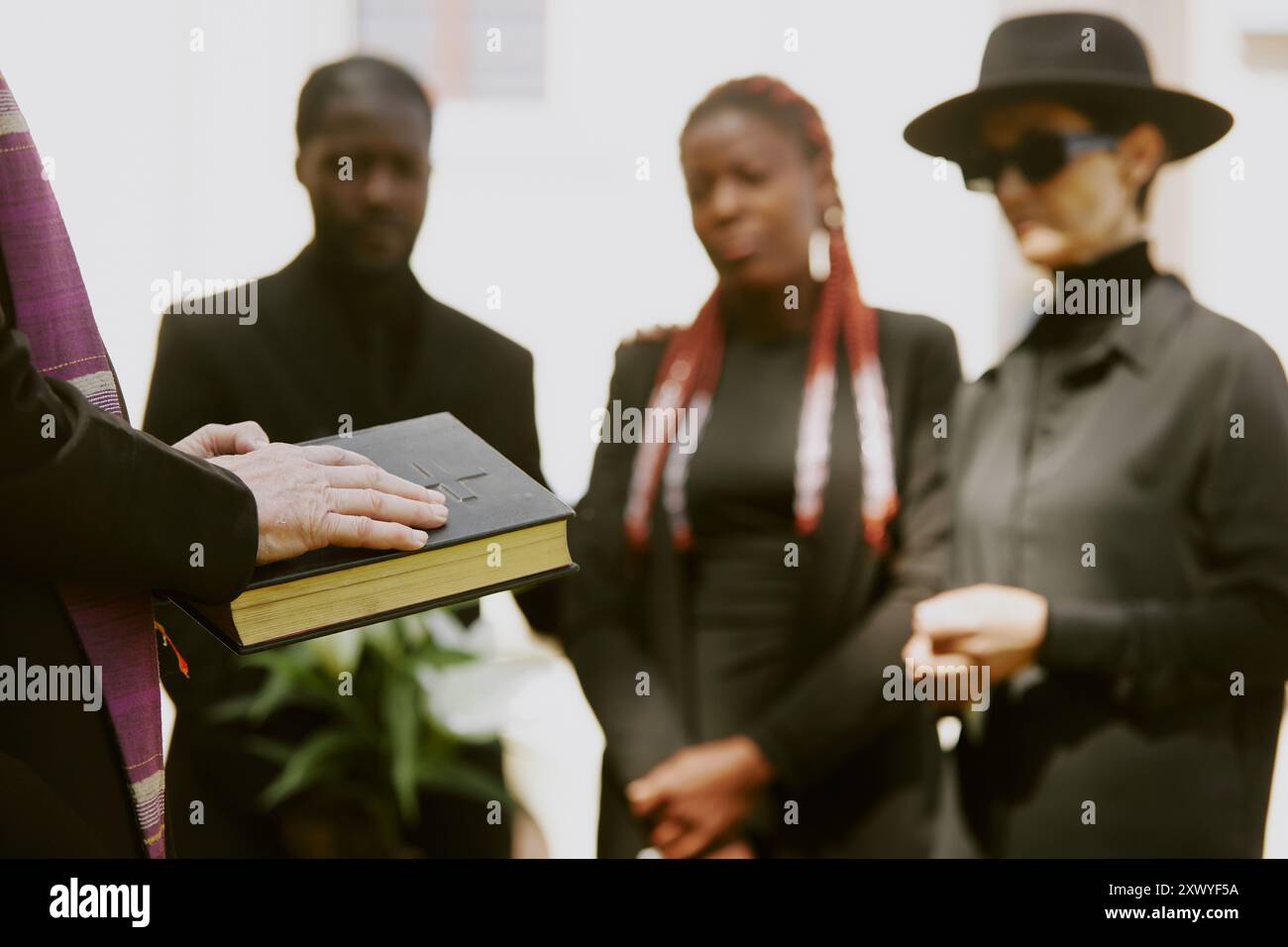 Unrecognizable pastors hands holding black leather bible while biracial ...