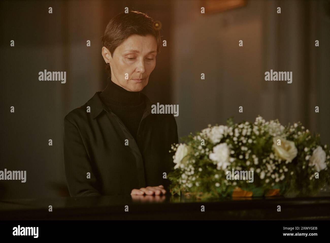 Senior mourning widow touching black coffin as goodbye gesture Stock ...