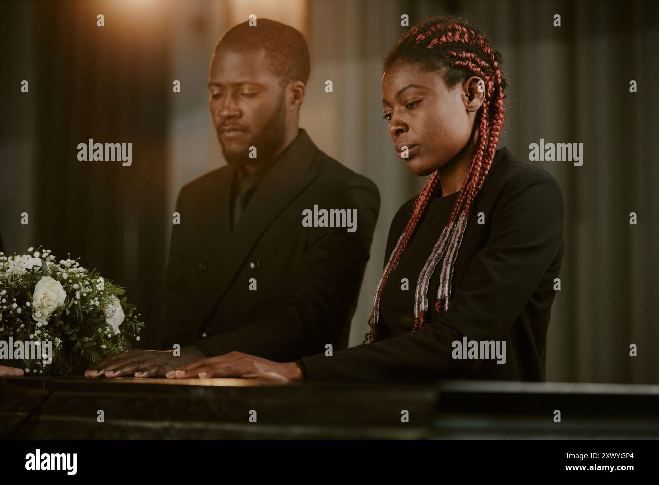 Crying African American woman and doleful man touching coffin Stock ...