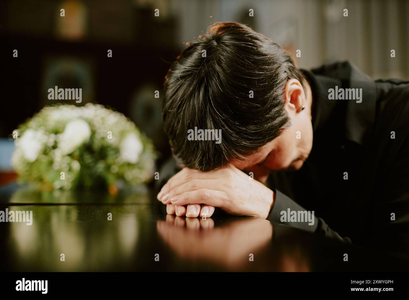 Doleful senior woman crying on black coffin in church during funeral ...