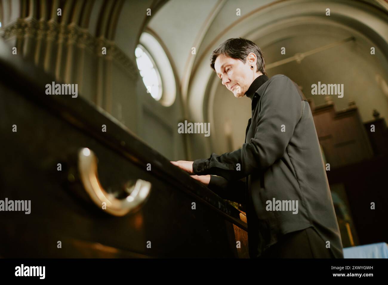 Low angle shot of Caucasian widow standing next to black wooden coffing ...