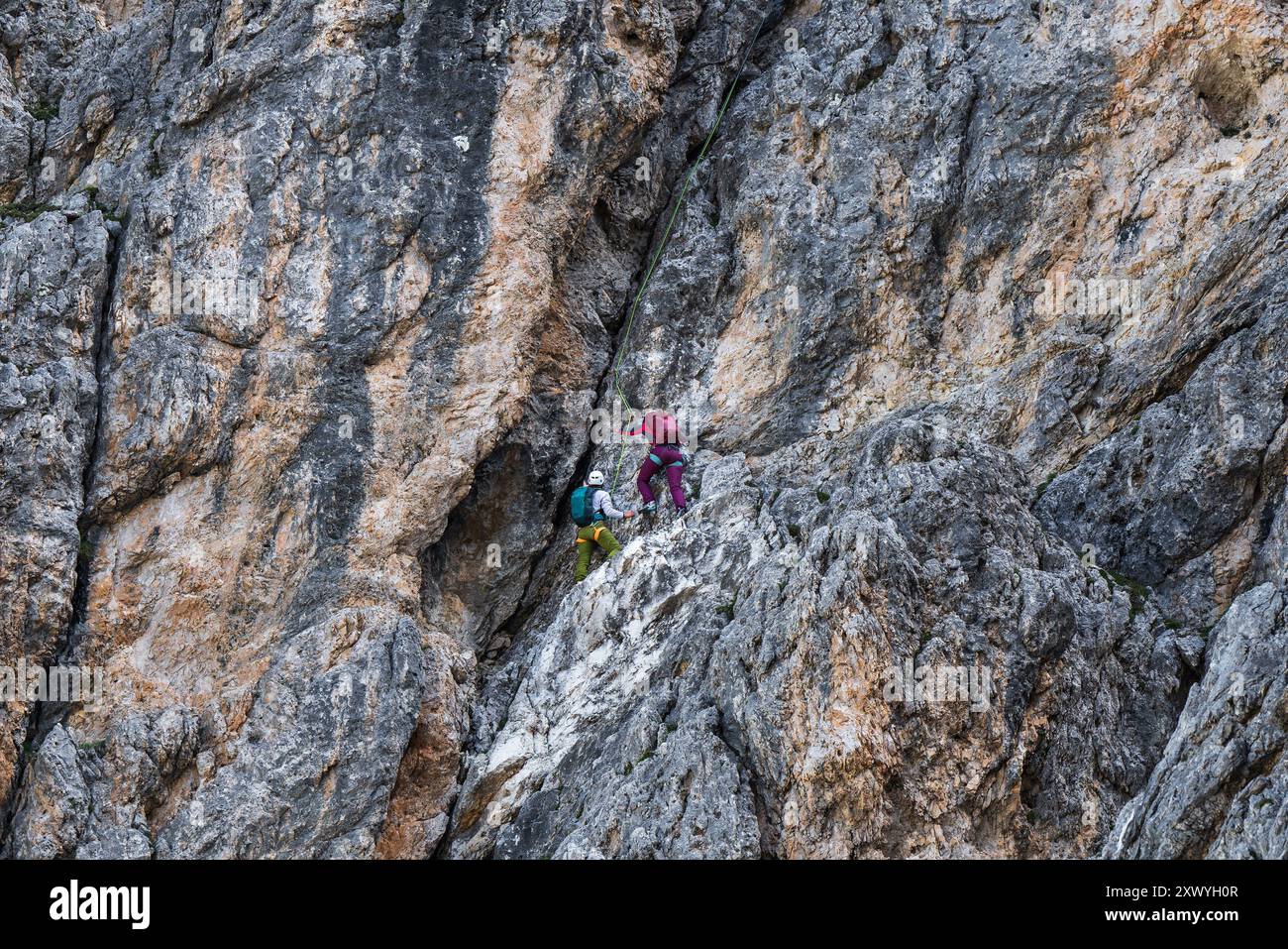 Two rock climbers climb a massive cliff on a sunny day. Extreme sports ...