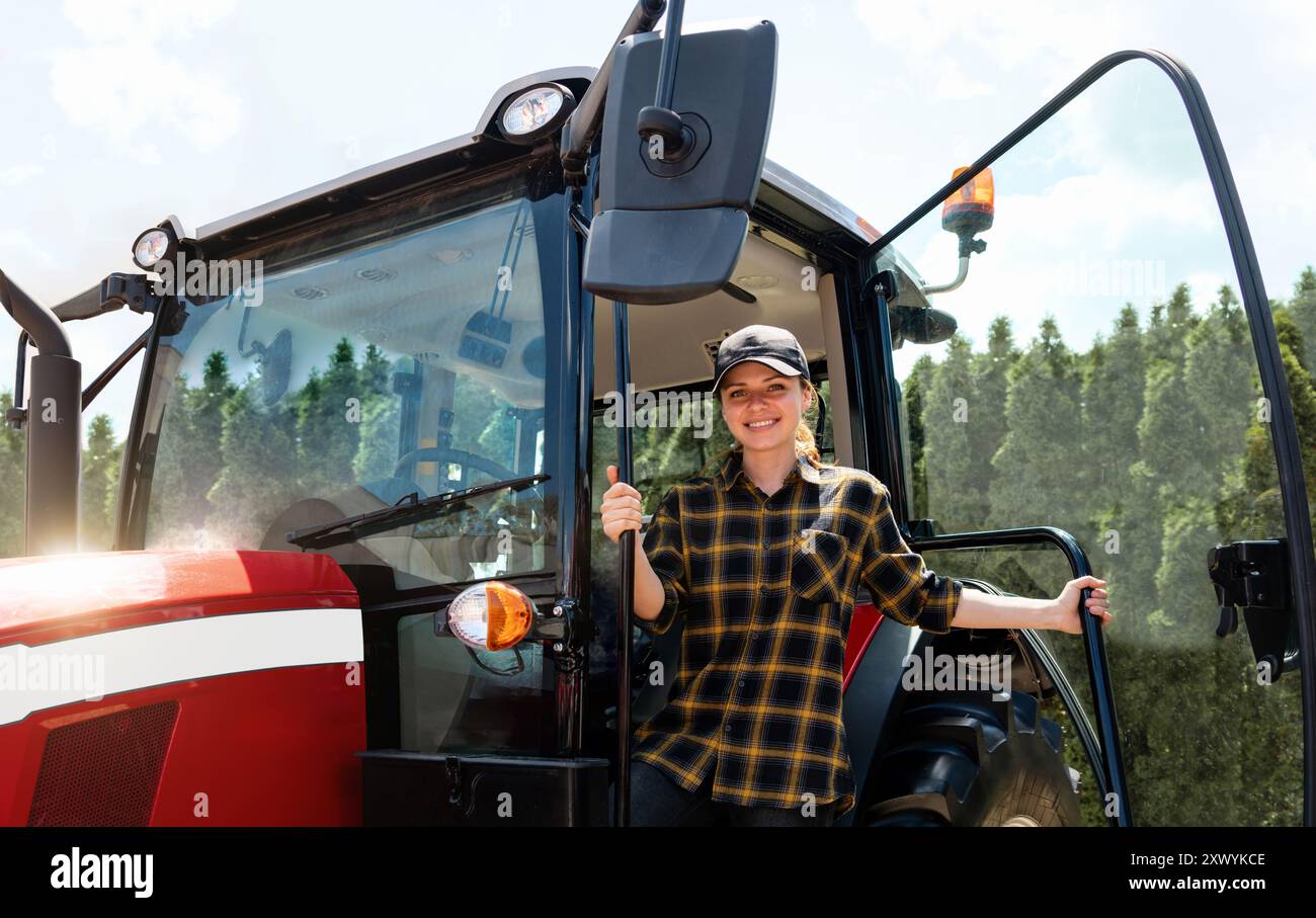 Portrait of female farm worker next to a red colored farm tractor ...