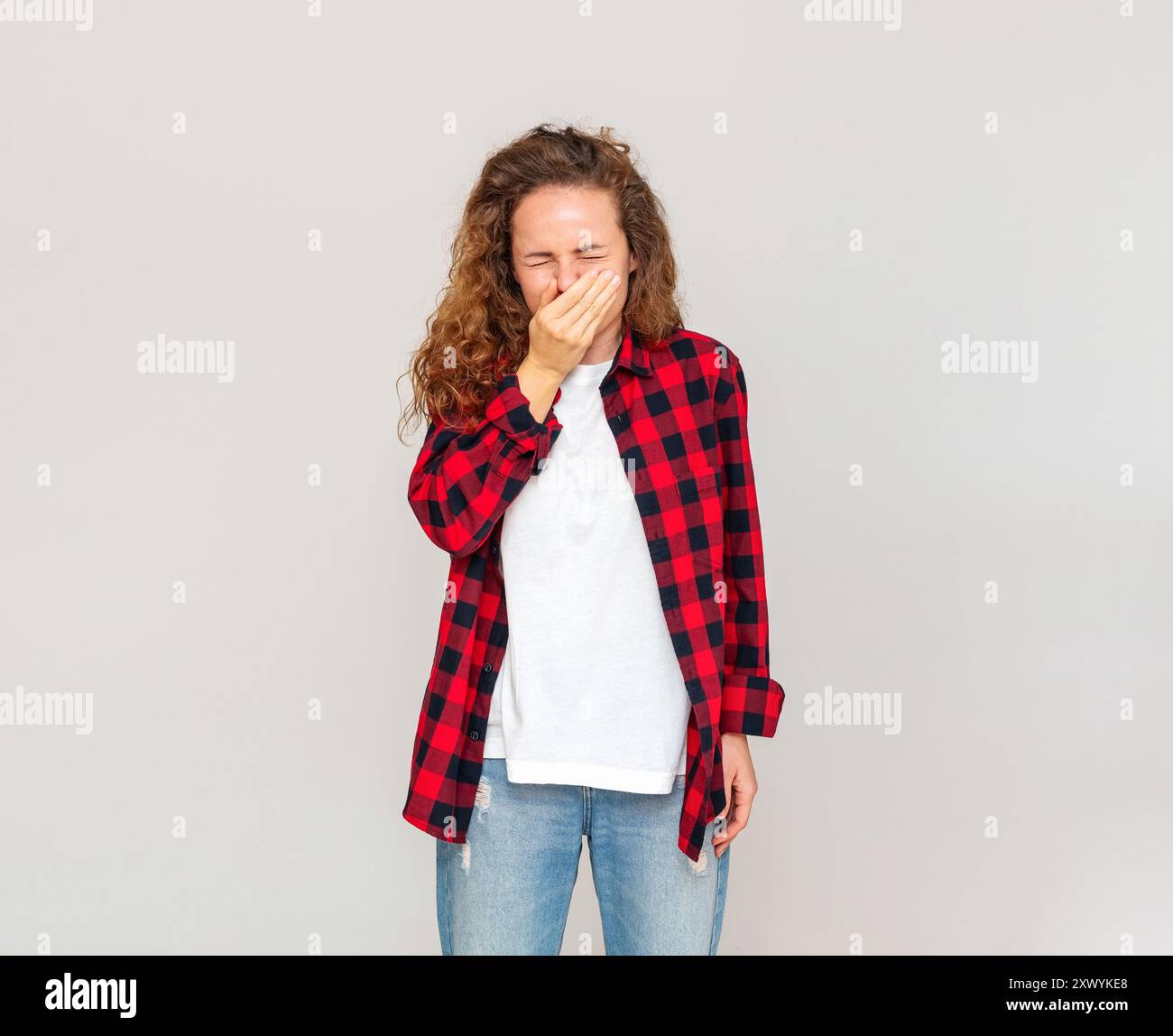 curly woman wearing casual outfit sneezing on plain light grey ...