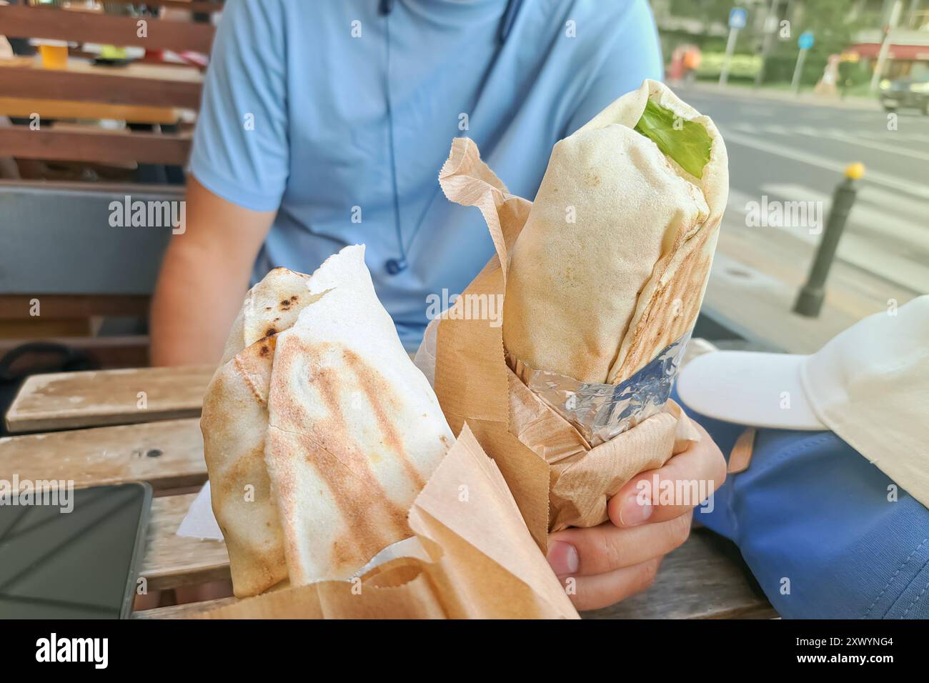 Two shawarmas, close-up. A man holds a shawarma in his hand. Street ...