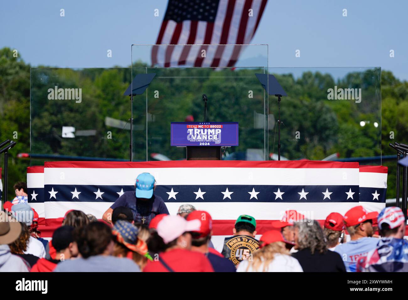 An outdoor stage is set encased with bulletproof glass as supporters ...