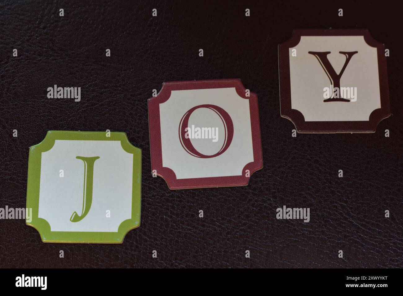 The word JOY formed with block style letters on a dark, textured ...