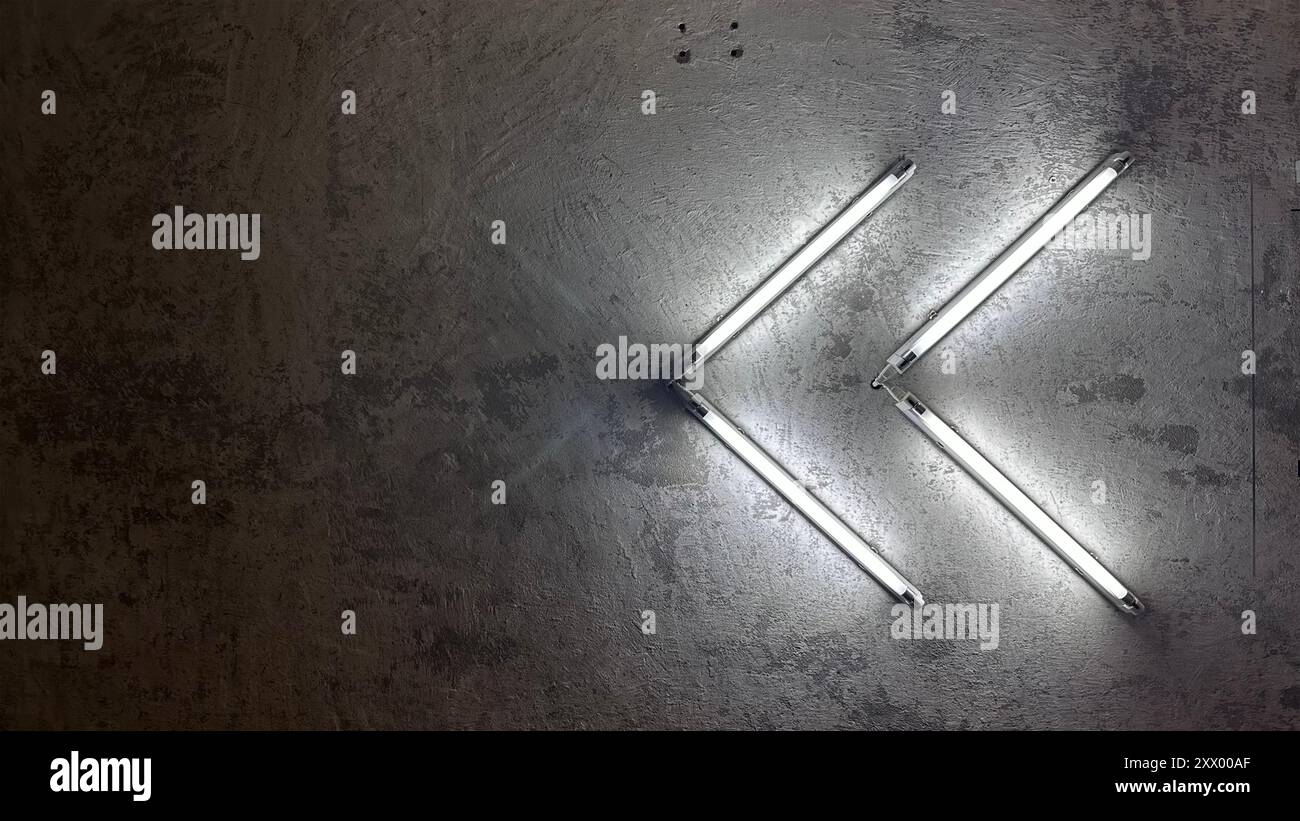 An arrangement of fluorescent light tubes forming an arrow pointing to ...