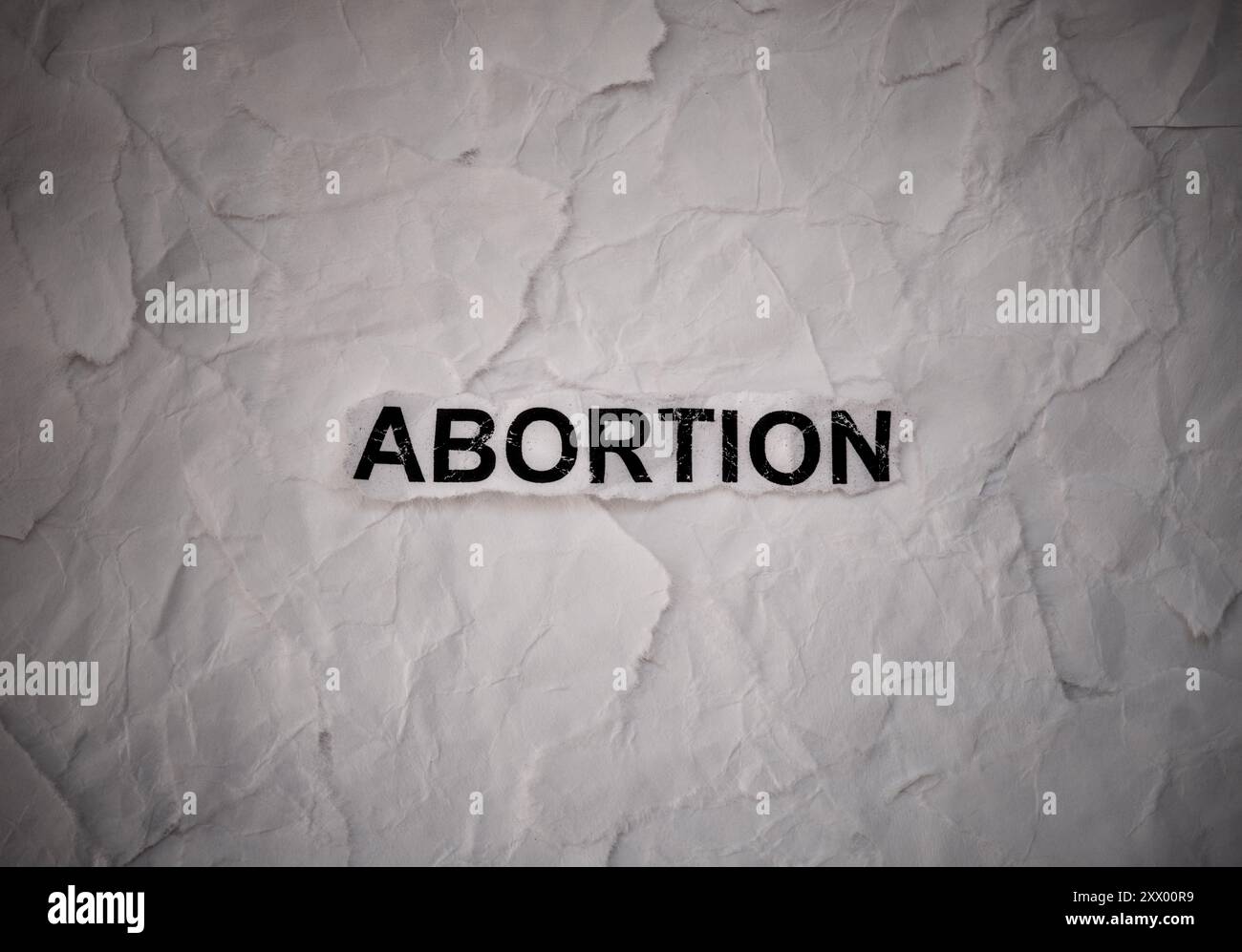 Crumpled piece of paper with word Abortion on a torn white paper pieces ...