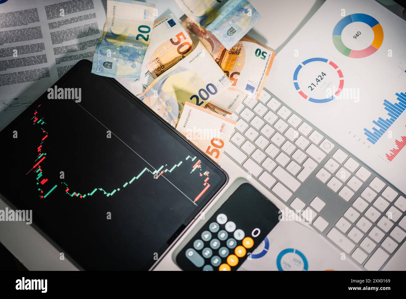 Stock charts on tablet screen. Desk from above. Euro currency banknotes ...