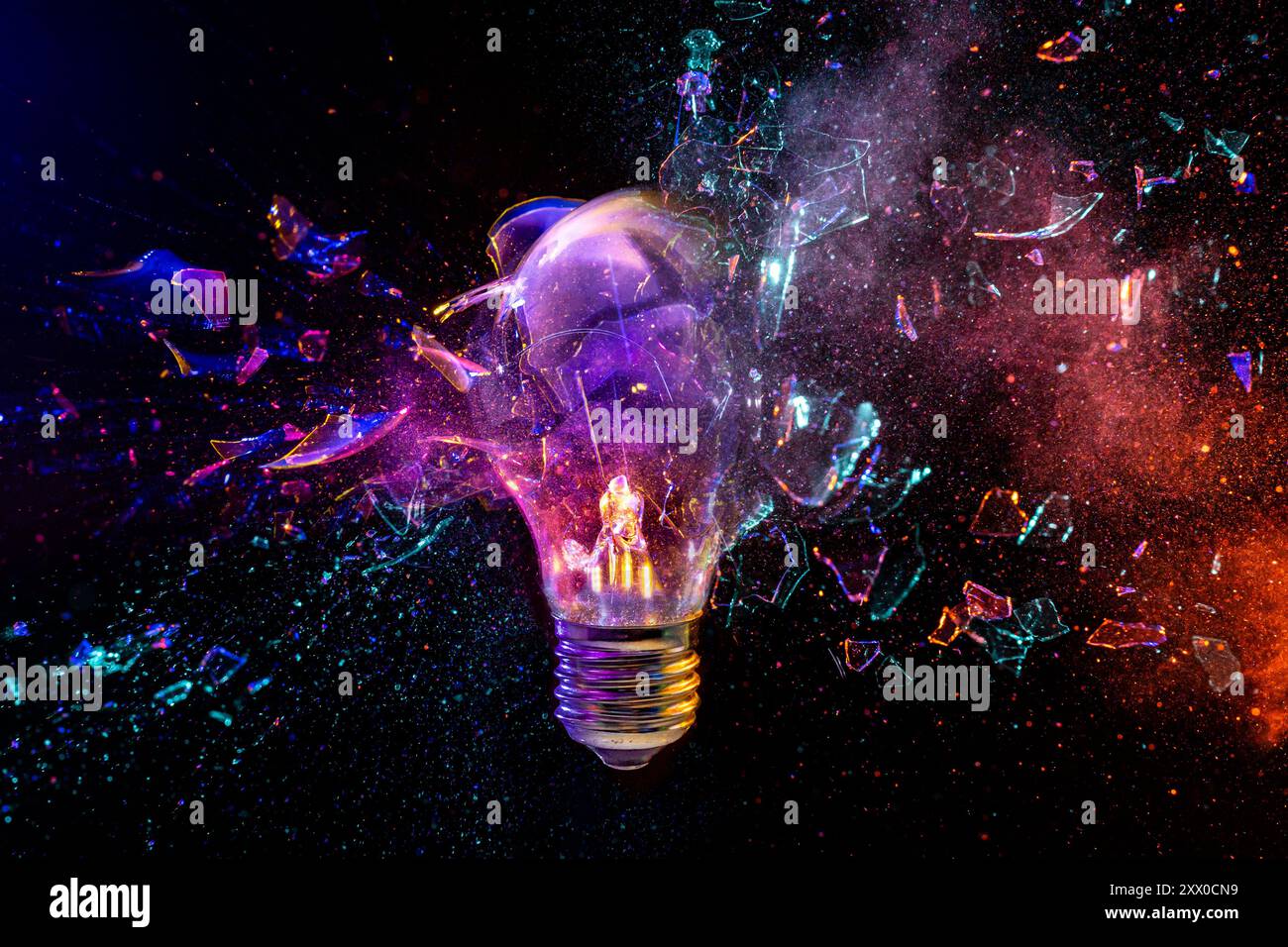 Light bulb is exploding while emitting colorful powder on a black ...