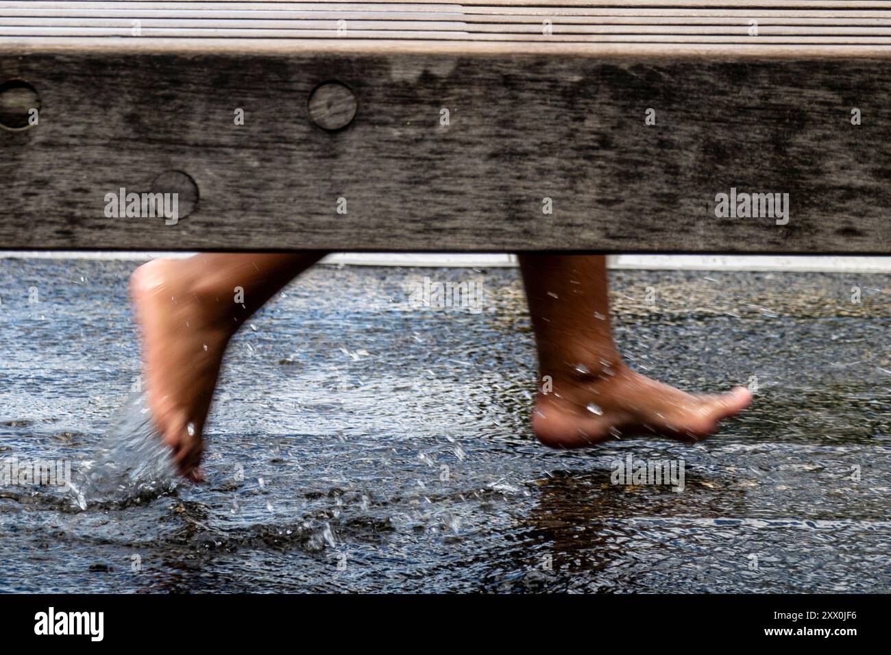 Brown children's feet running through water on the High Line Park, New ...