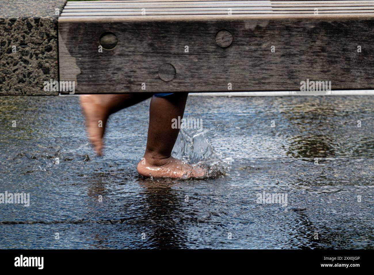 Brown children's feet running through water on the High Line Park, New ...