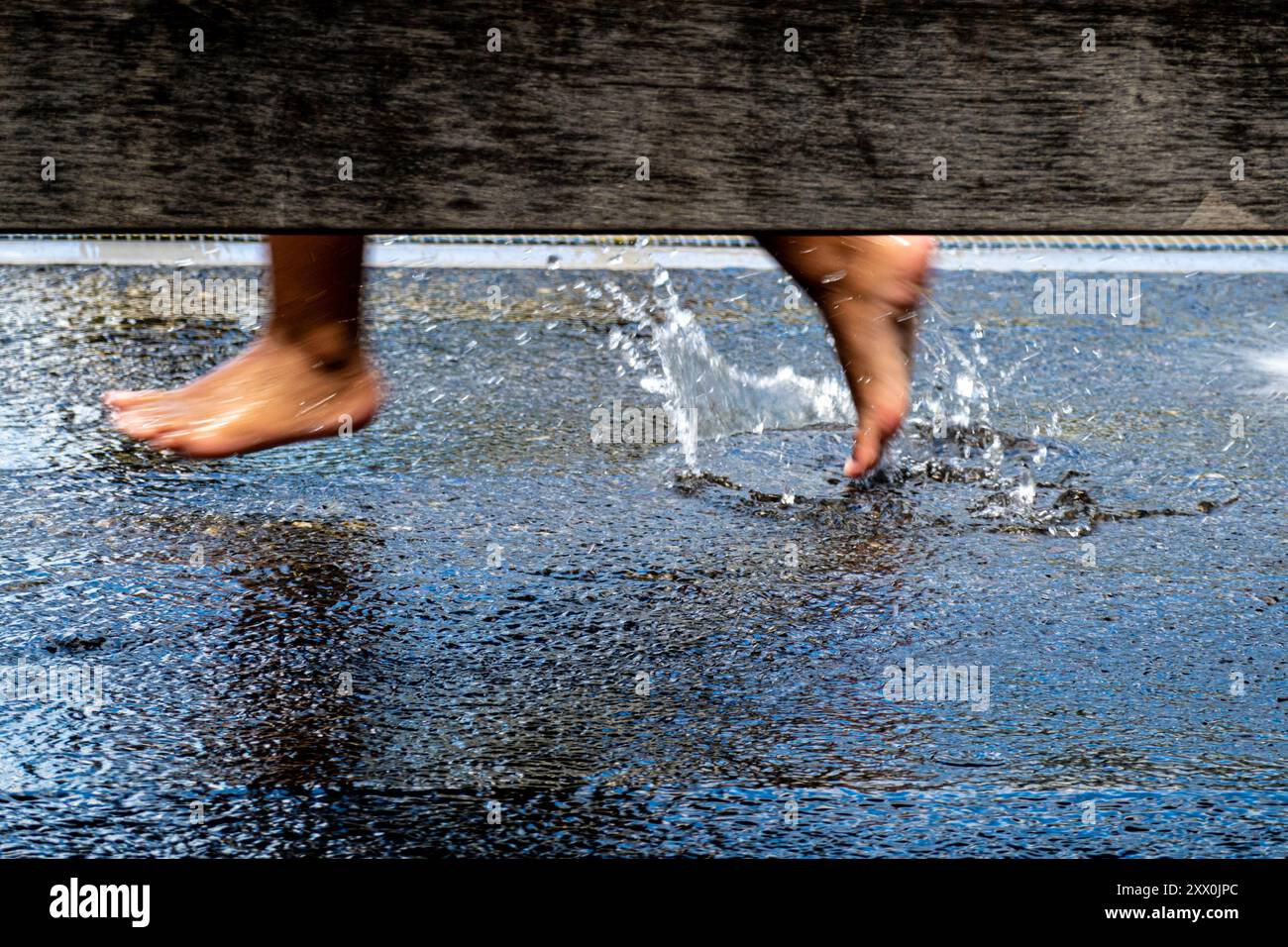 Brown children's feet running through water on the High Line Park, New ...