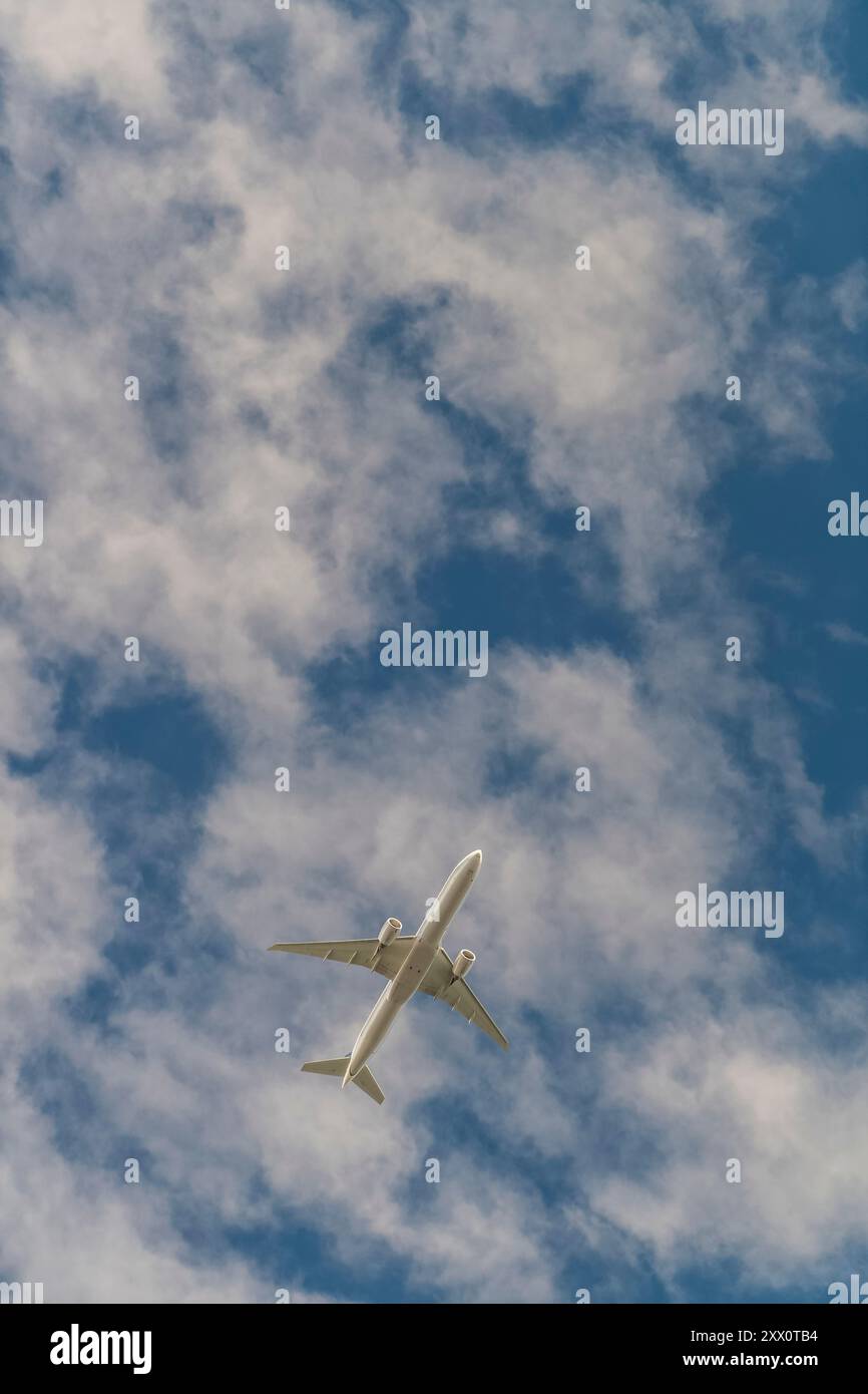 A commercial airplane flying high in the sky with scattered clouds ...