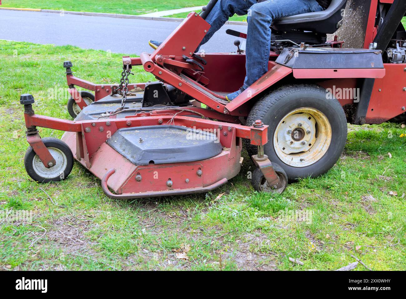 An employee of city mows grass in park with lawn mower tractor during landscaping operations ...