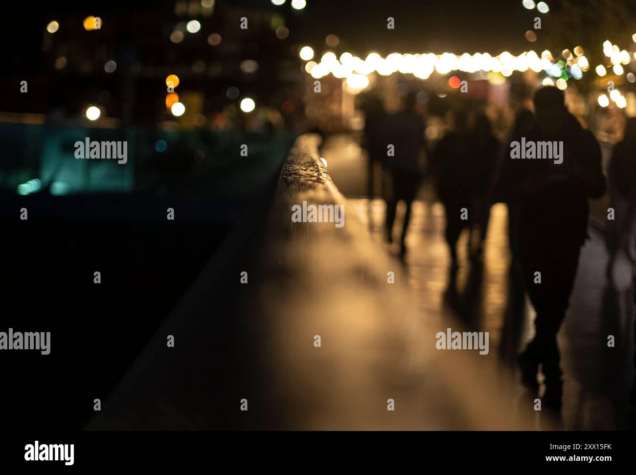 Pedestrians and cyclists walk across a bridge at night in Copenhagen ...