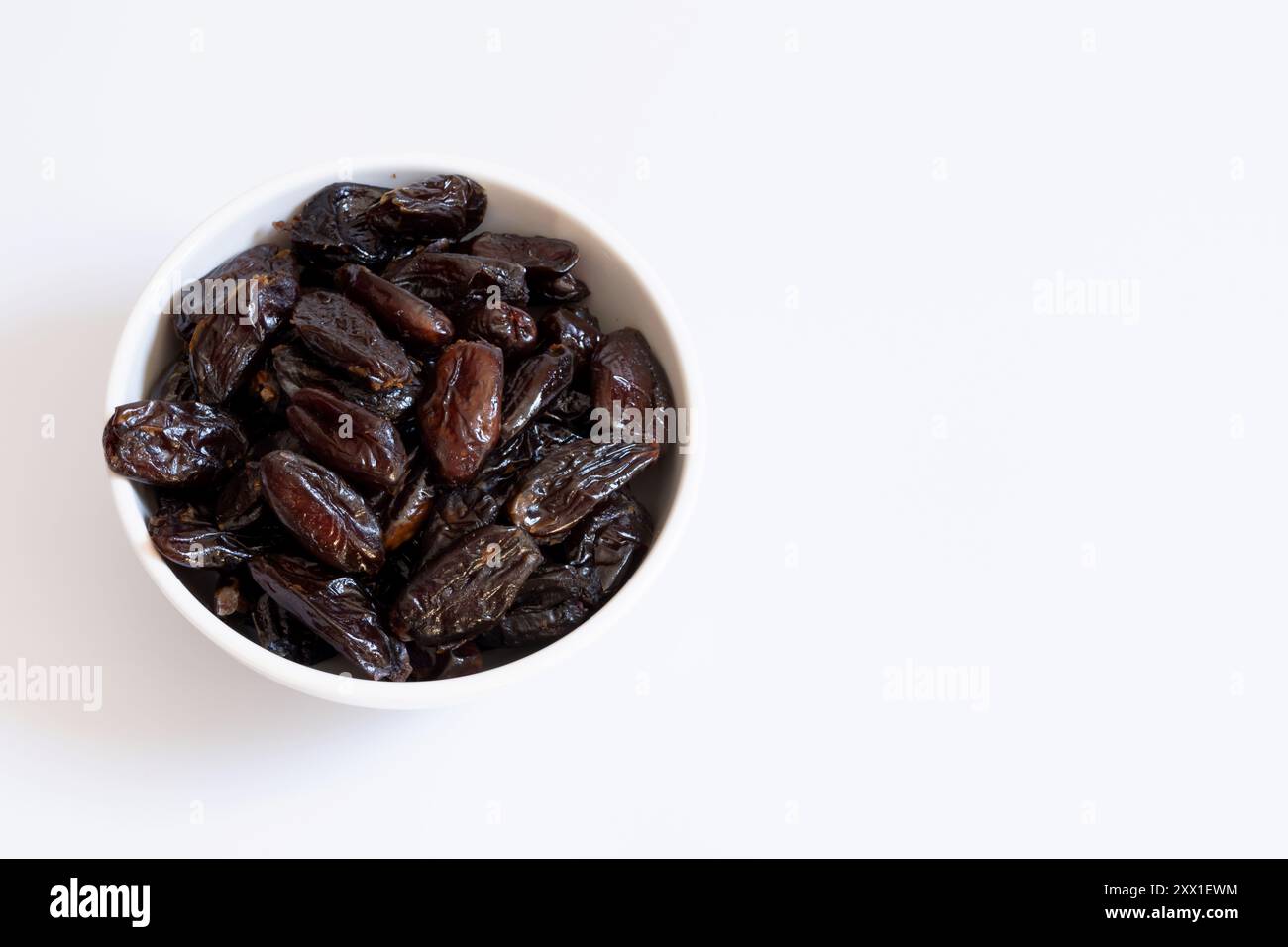 Dates inside a white bowl on a white background Stock Photo - Alamy