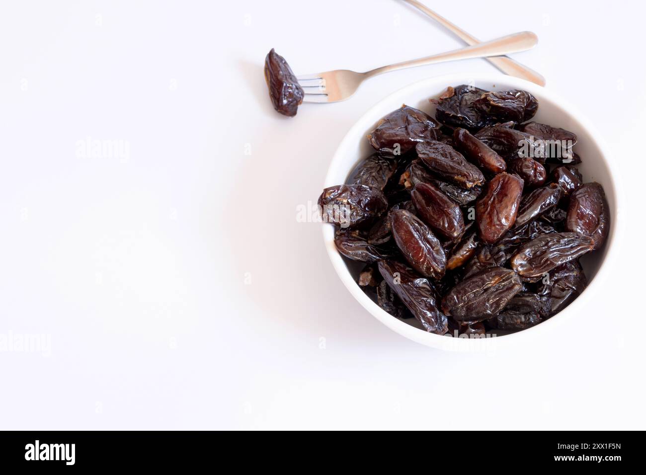 Dates inside a bowl on a white background with a dessert fork Stock ...