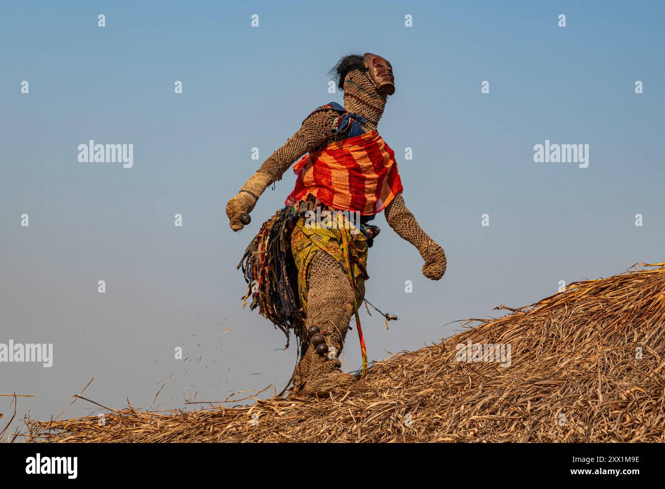 Traditional masked man dancing on a roof of a hut, Tshikapa, Kasai ...