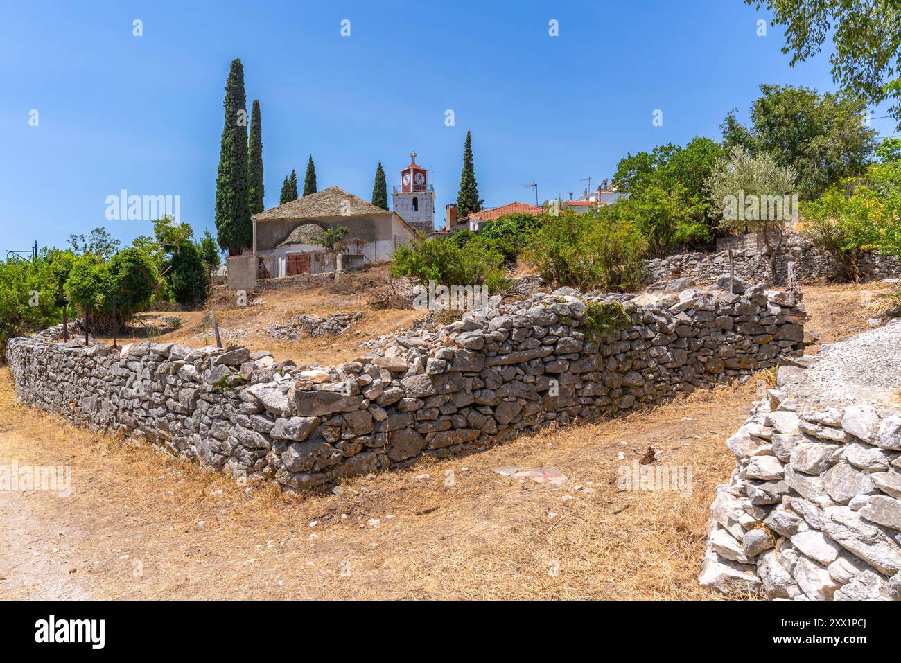 View of dry stone walls and clock tower of Greek Orthodox Church ...