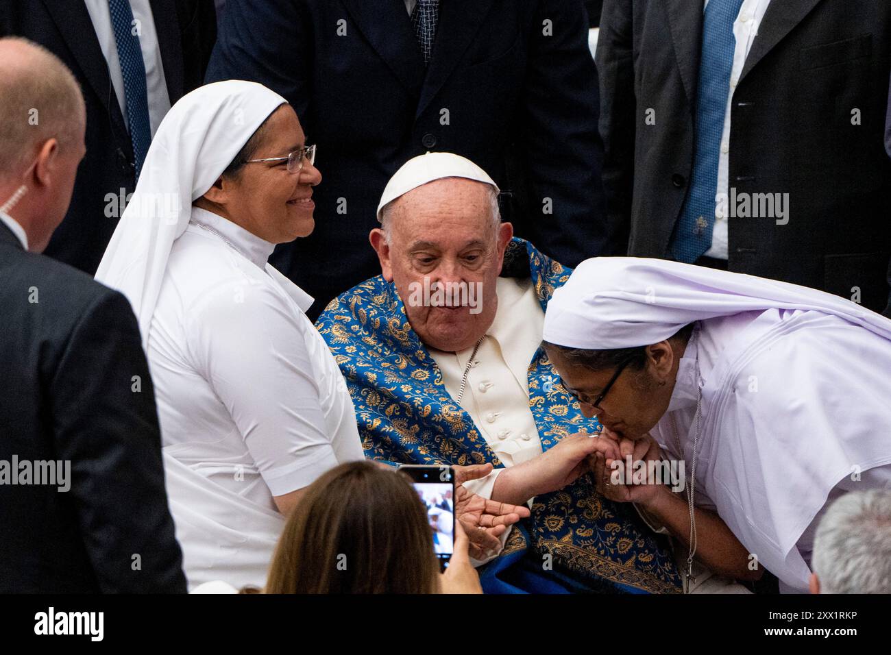 A nun kisses the hand of Pope Francis during his traditional Wednesday ...