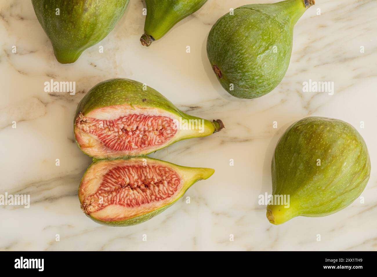 cut half of green fig fruit on white marble Stock Photo - Alamy