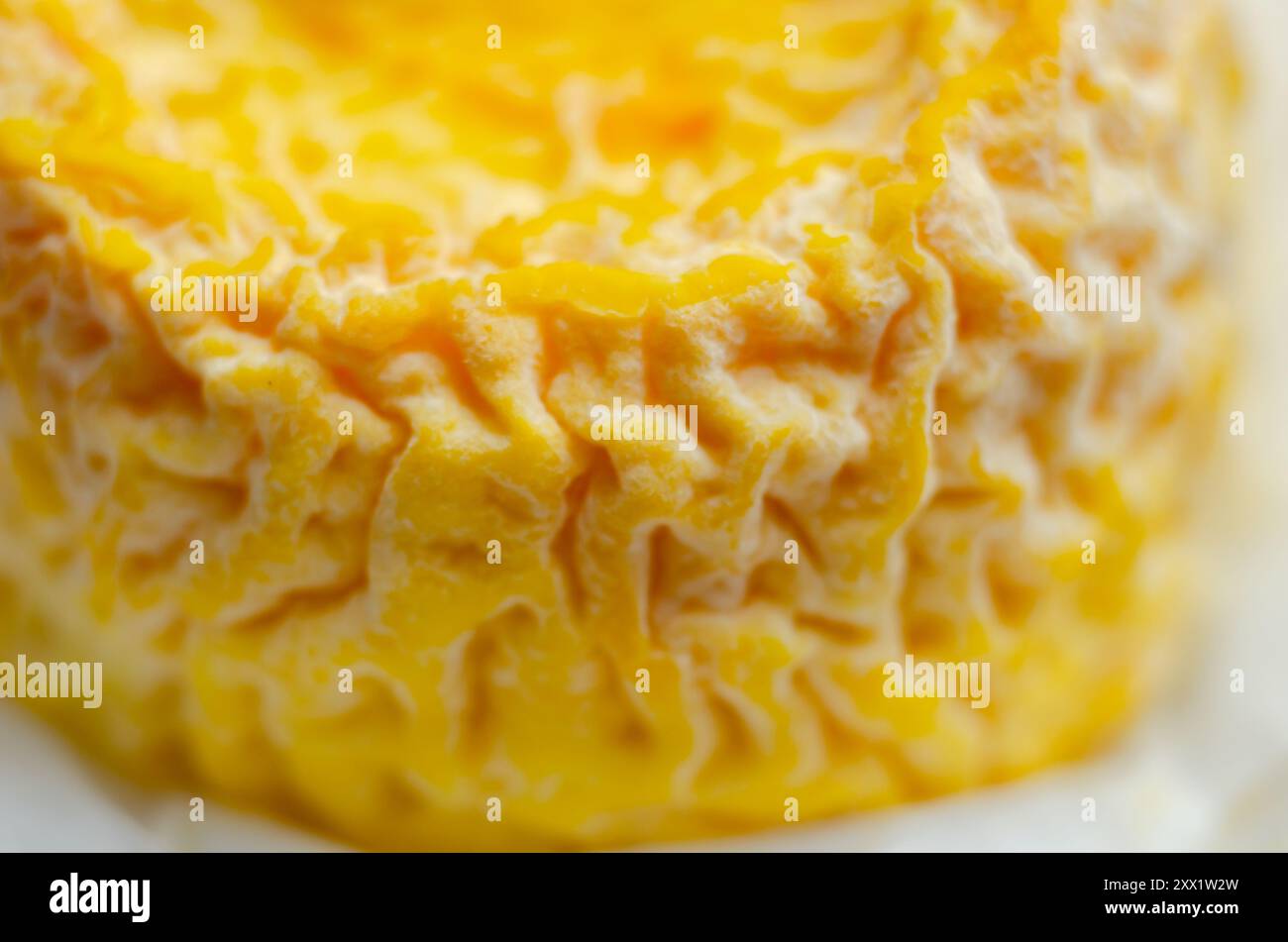 A yellow cheese is sitting in a paper wrapper, popular soft french ...