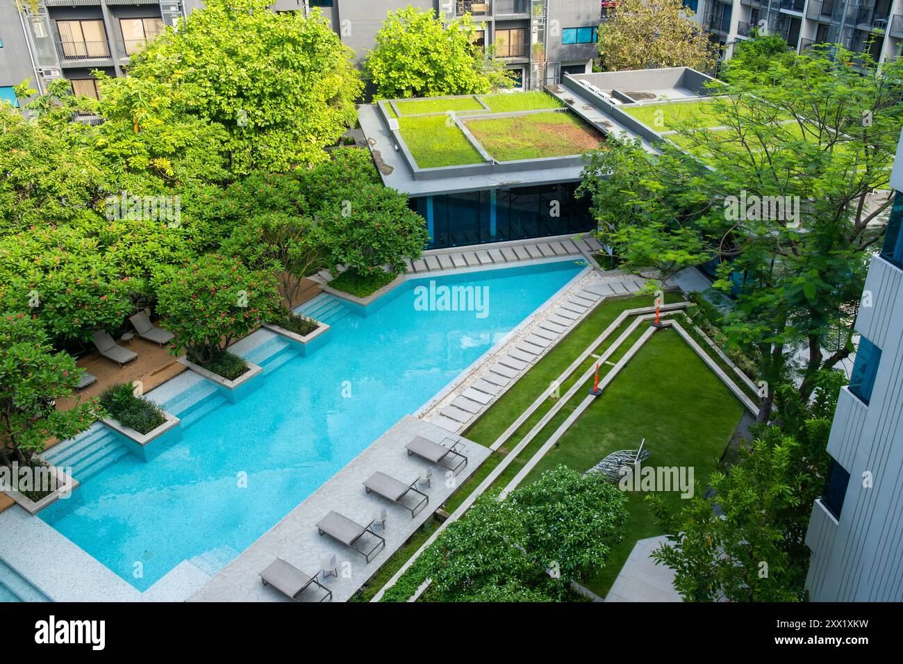Modern apartment complex with large outdoor swimming pool, lush ...